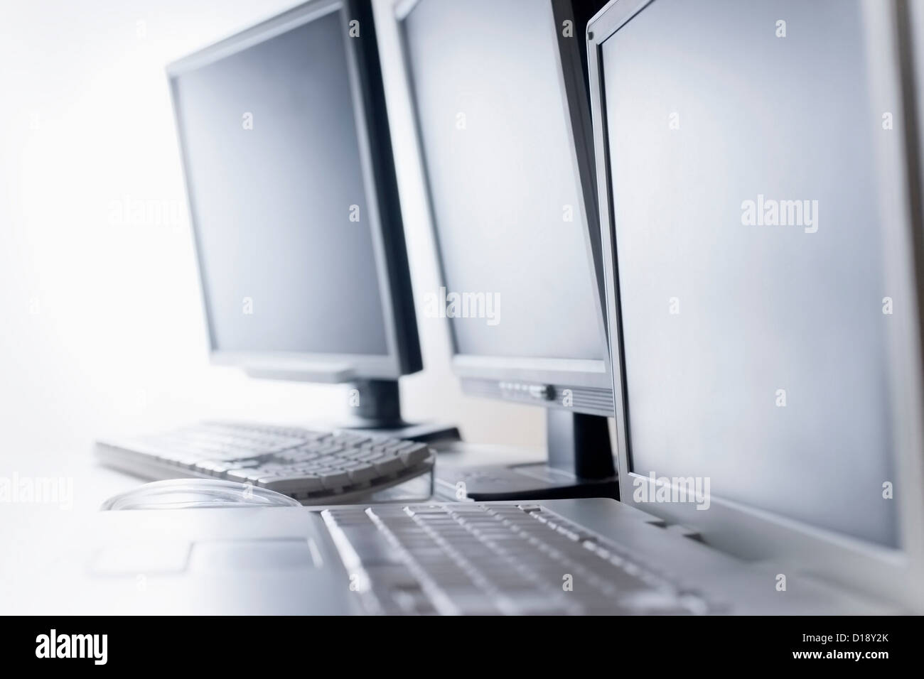 Computer screens and laptop on desk Stock Photo - Alamy