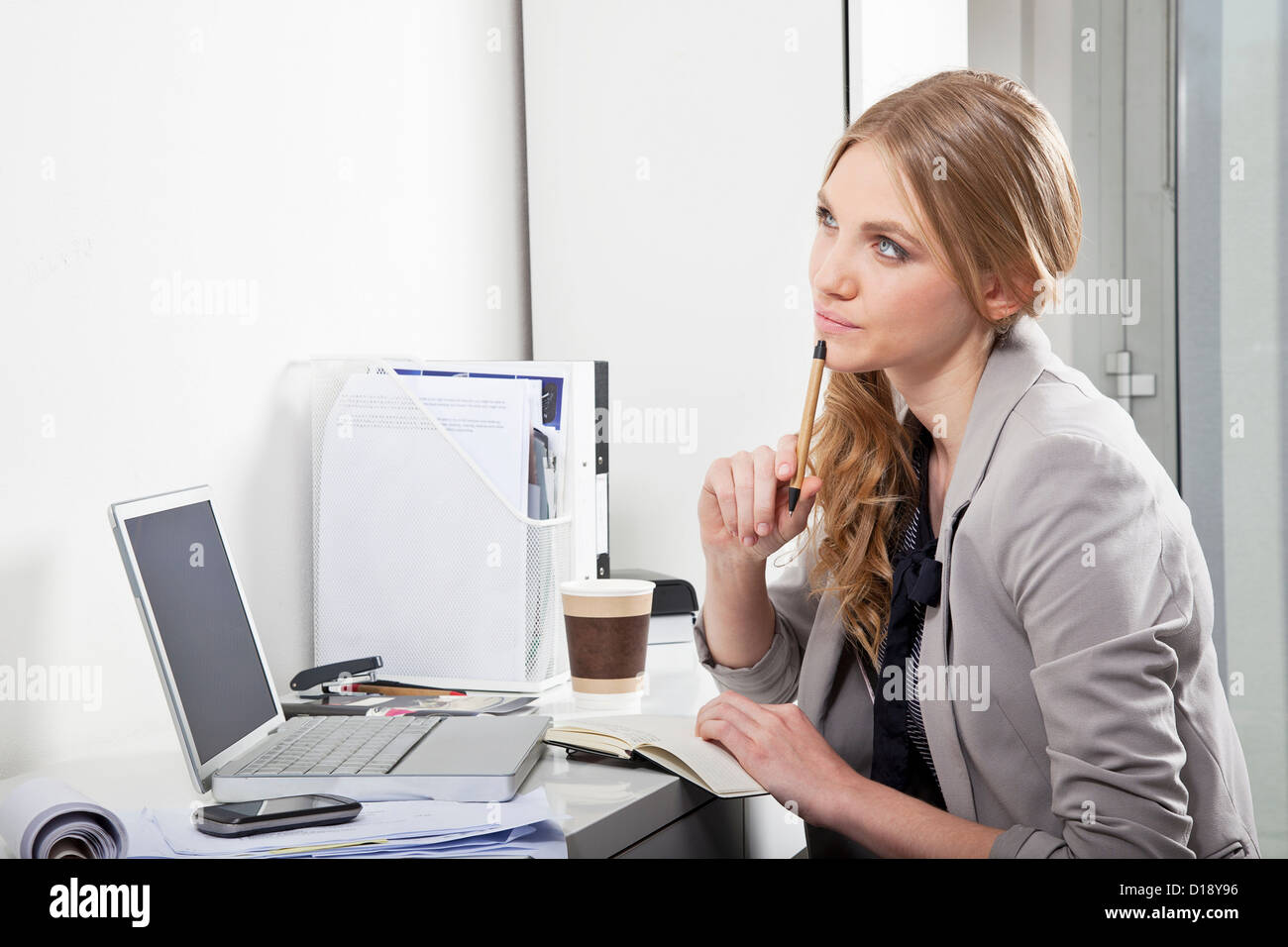 Young woman at her desk, thinking Stock Photo - Alamy