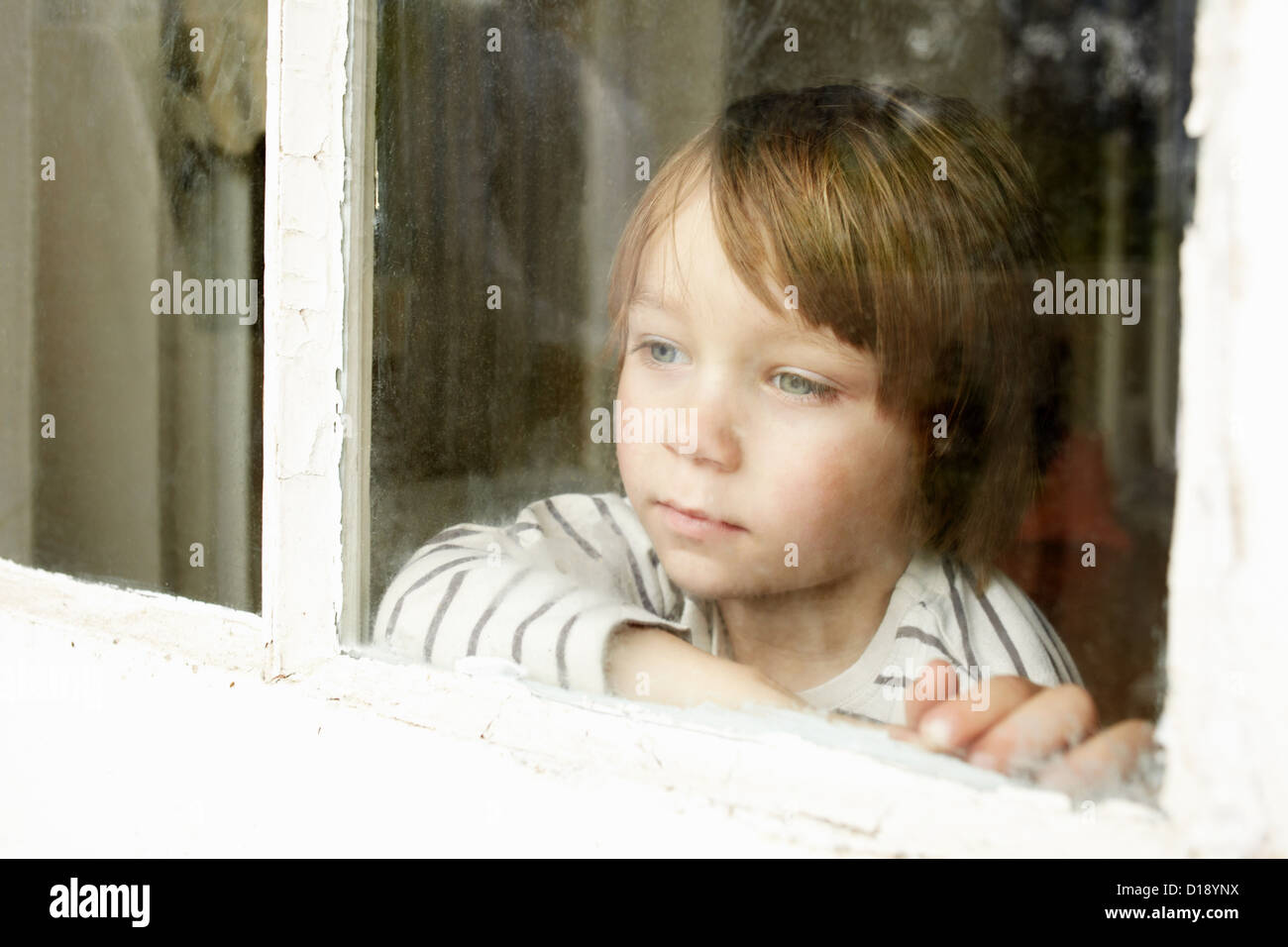 Little boy looking through window Stock Photo - Alamy