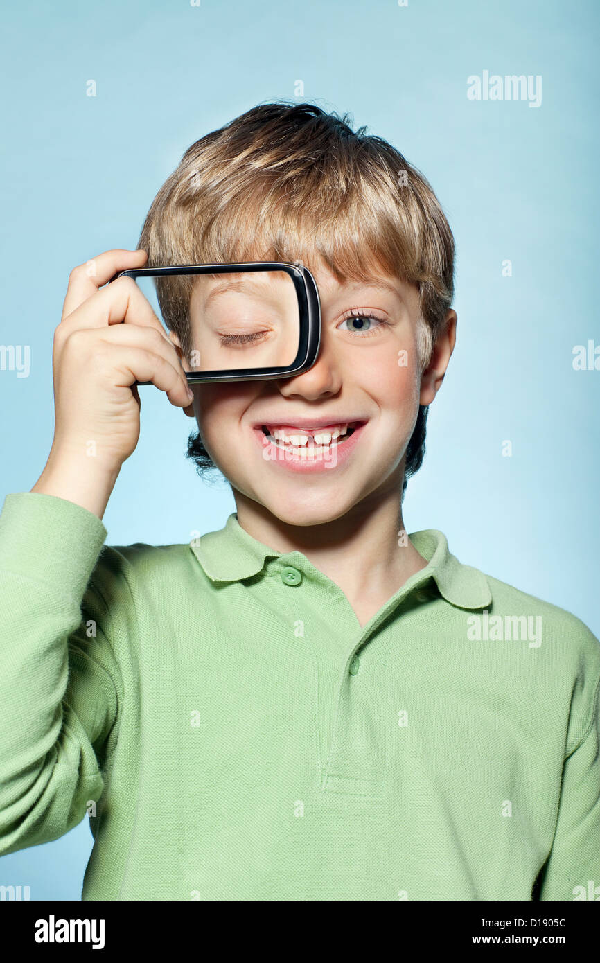 Boy holding smartphone over eye Stock Photo - Alamy