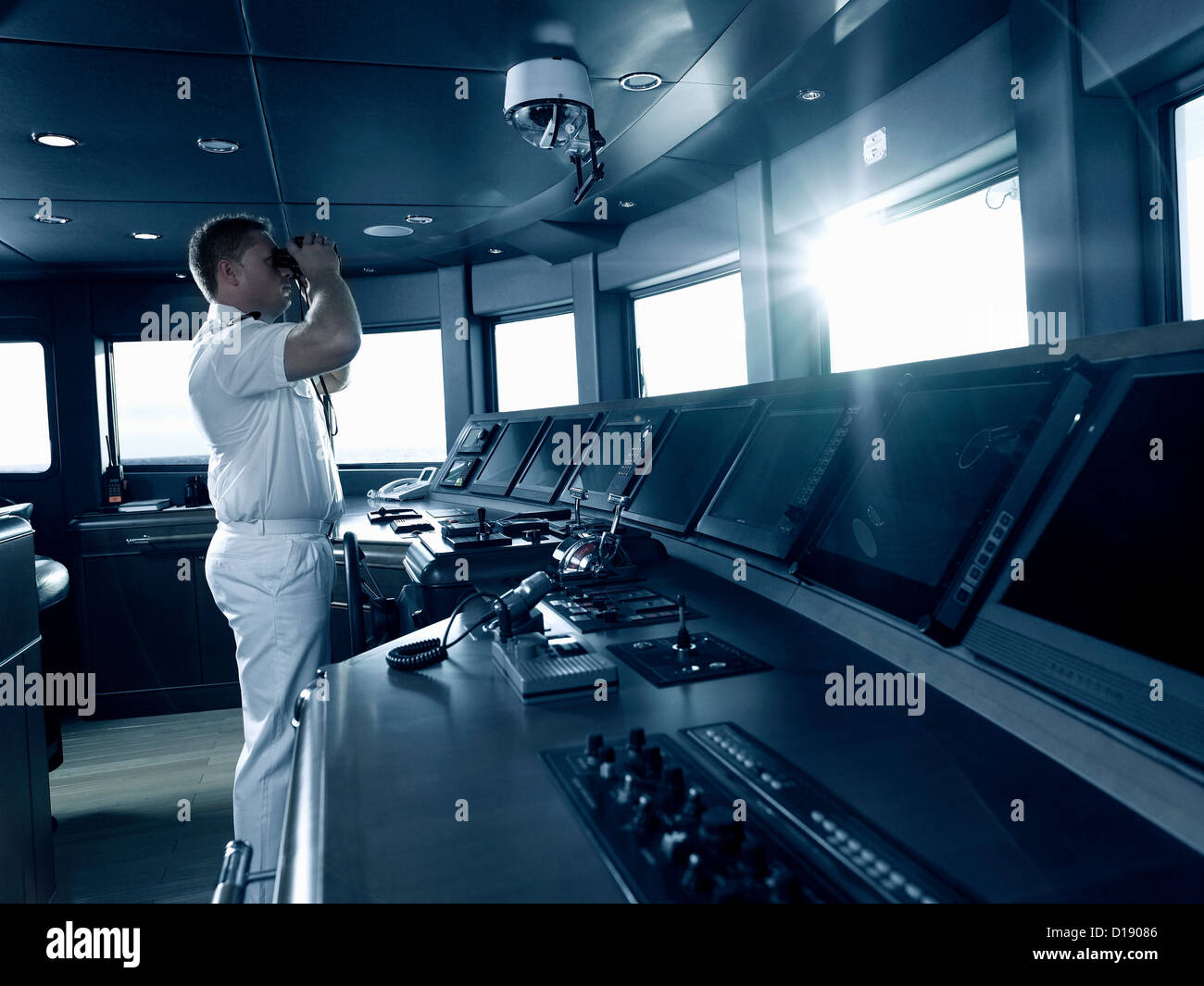 Captain in cockpit of motor yacht, using binoculars Stock Photo - Alamy