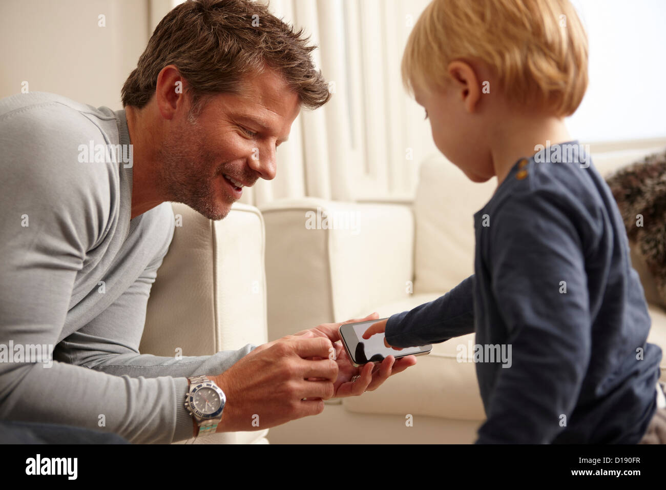Father holding smartphone, son using touchscreen Stock Photo - Alamy