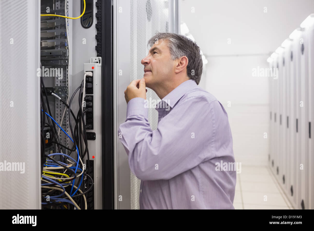 Man looking up thoughtfully into server locker Stock Photo - Alamy