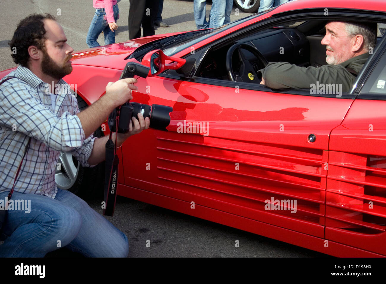 The driver of a red Ferrari having his photo taken by a photographer ...