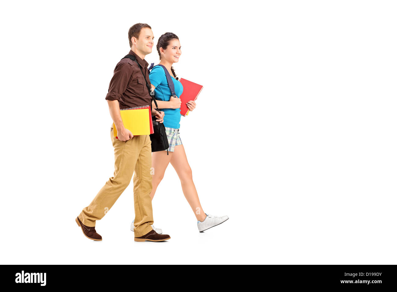 Full length portrait of a two students holding books and walking ...