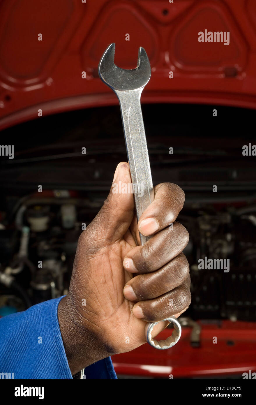 South African or American mechanic hand with spanner in front of car ...