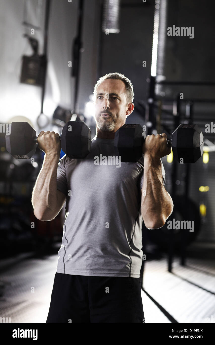 Man using dumbbells in a gym Stock Photo - Alamy