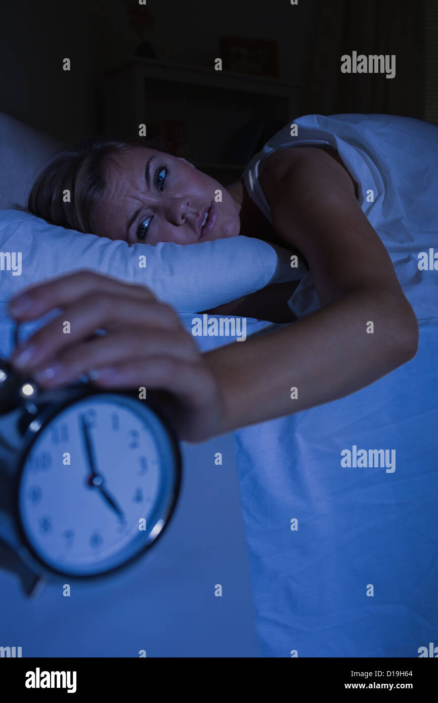 Blonde woman stopping her alarm clock Stock Photo - Alamy