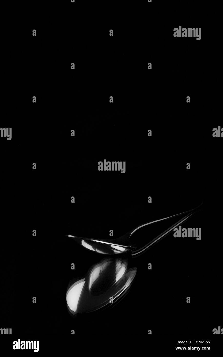 Single silver spoon reflecting in mirror with black background Stock ...