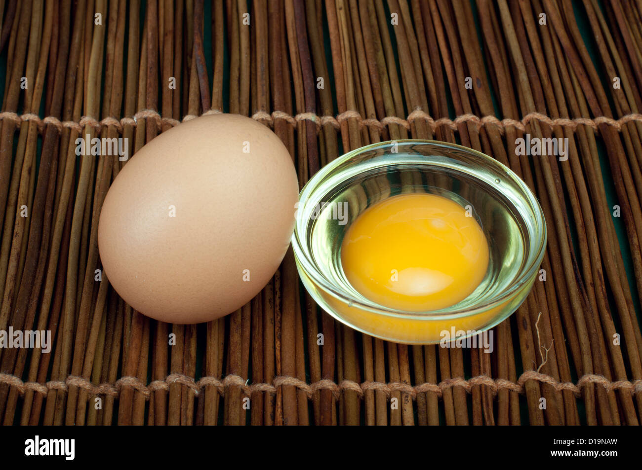 One whole egg and another broken in half raw egg and yolk inside ...