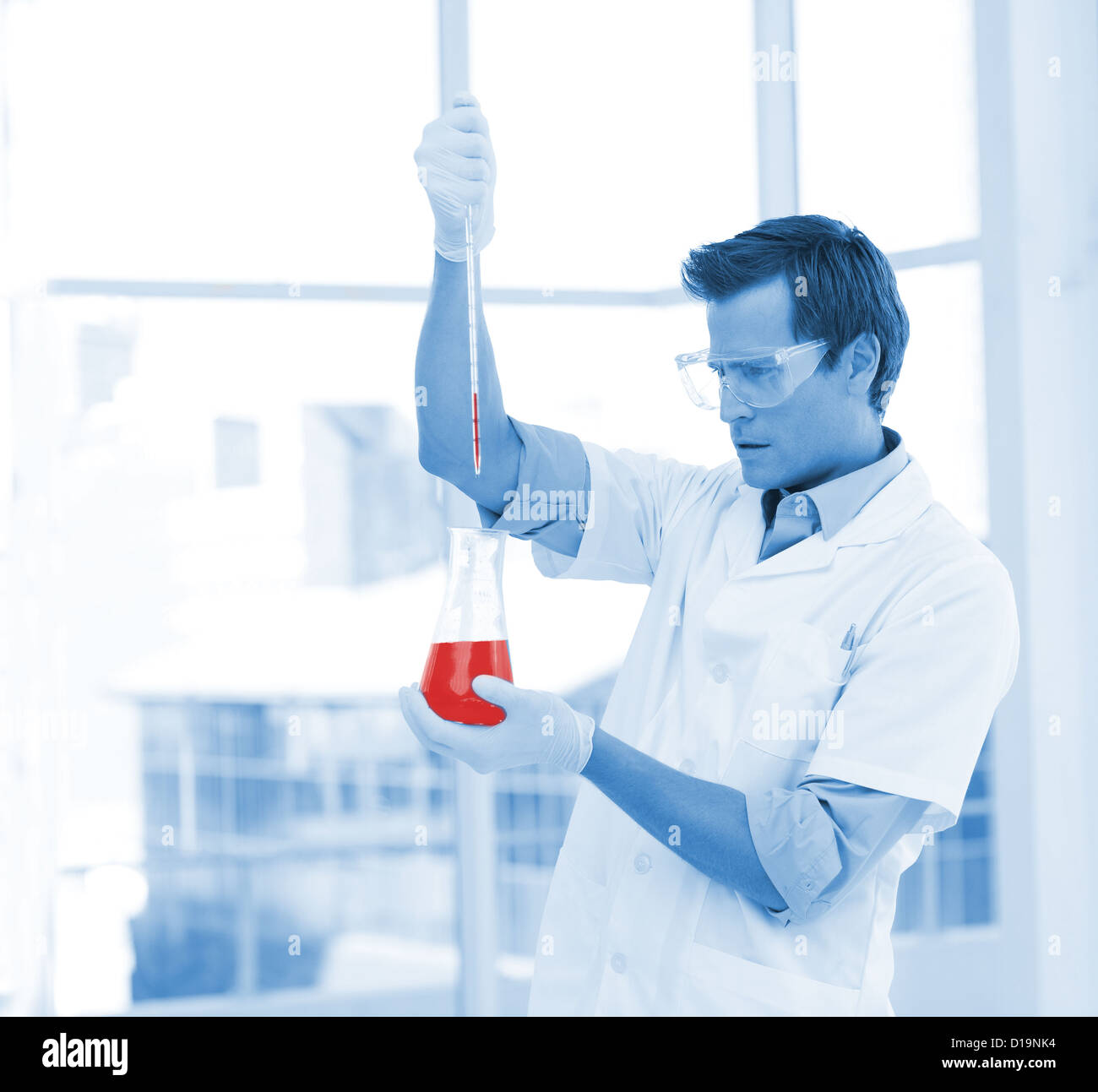 Serious scientist taking sample from beaker Stock Photo - Alamy