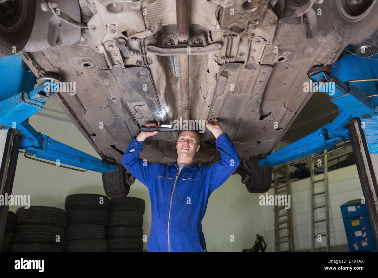 Mechanic inspecting under car Stock Photo - Alamy