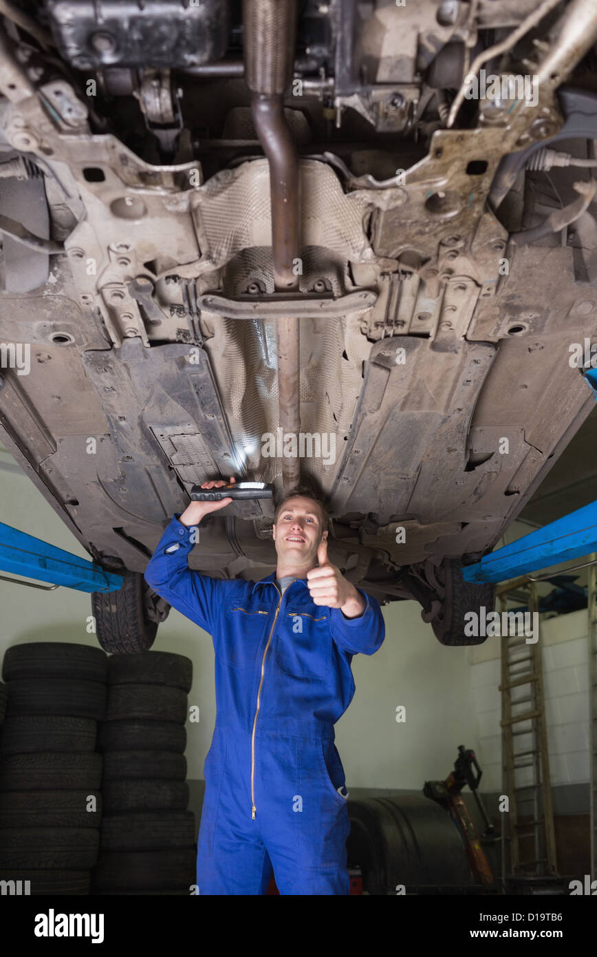 Male mechanic under car gesturing thumbs up Stock Photo - Alamy
