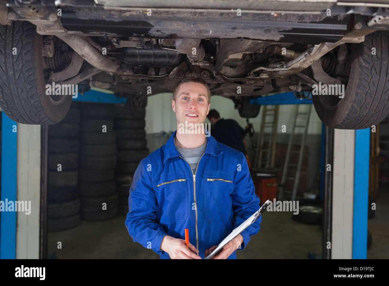 Mechanic with clipboard under car Stock Photo - Alamy