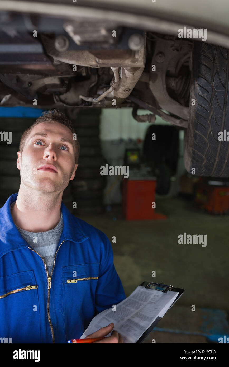 Mechanic with clipboard examining car Stock Photo - Alamy