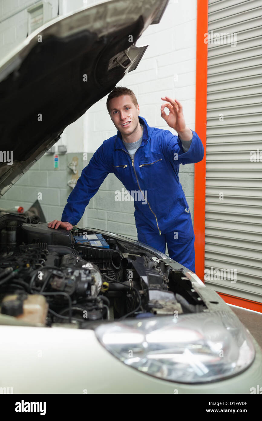 Mechanic by car making ok sign Stock Photo - Alamy