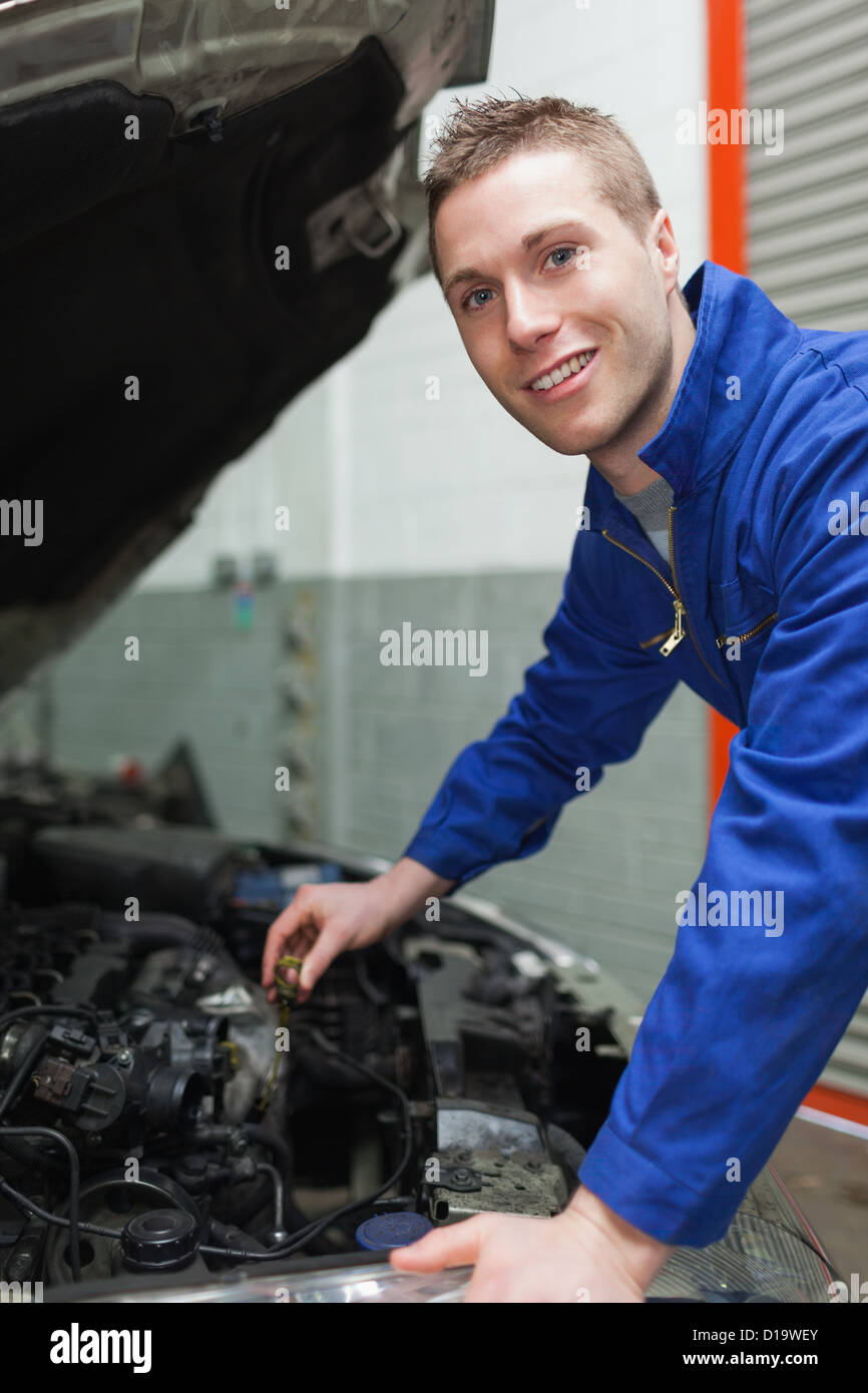 Auto mechanic checking car engine oil Stock Photo - Alamy
