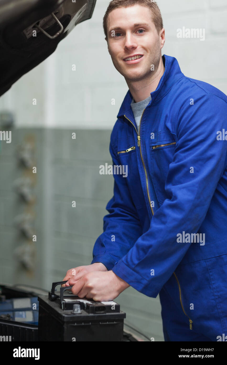 Happy male mechanic with car battery Stock Photo - Alamy