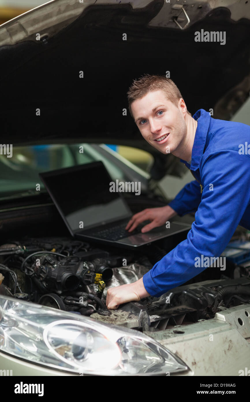 Car mechanic with laptop checking engine Stock Photo - Alamy