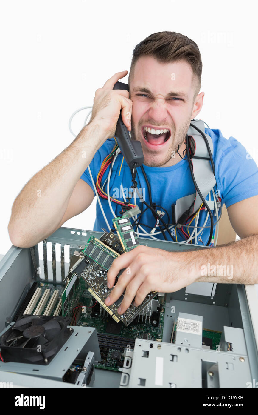 Frustrated computer engineer screaming over the phone in front of open ...