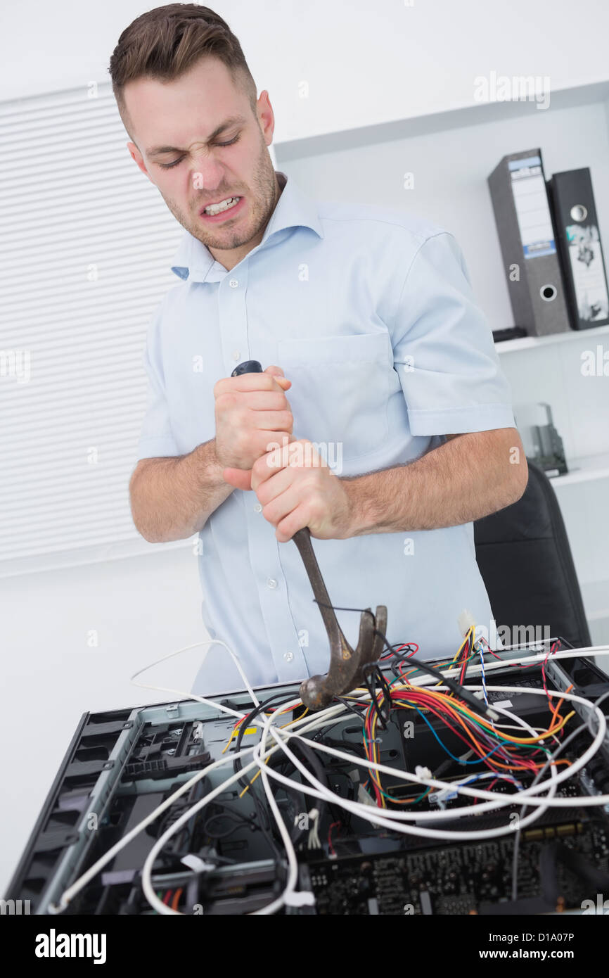 Frustrated man using hammer to pull out wires from cpu Stock Photo - Alamy