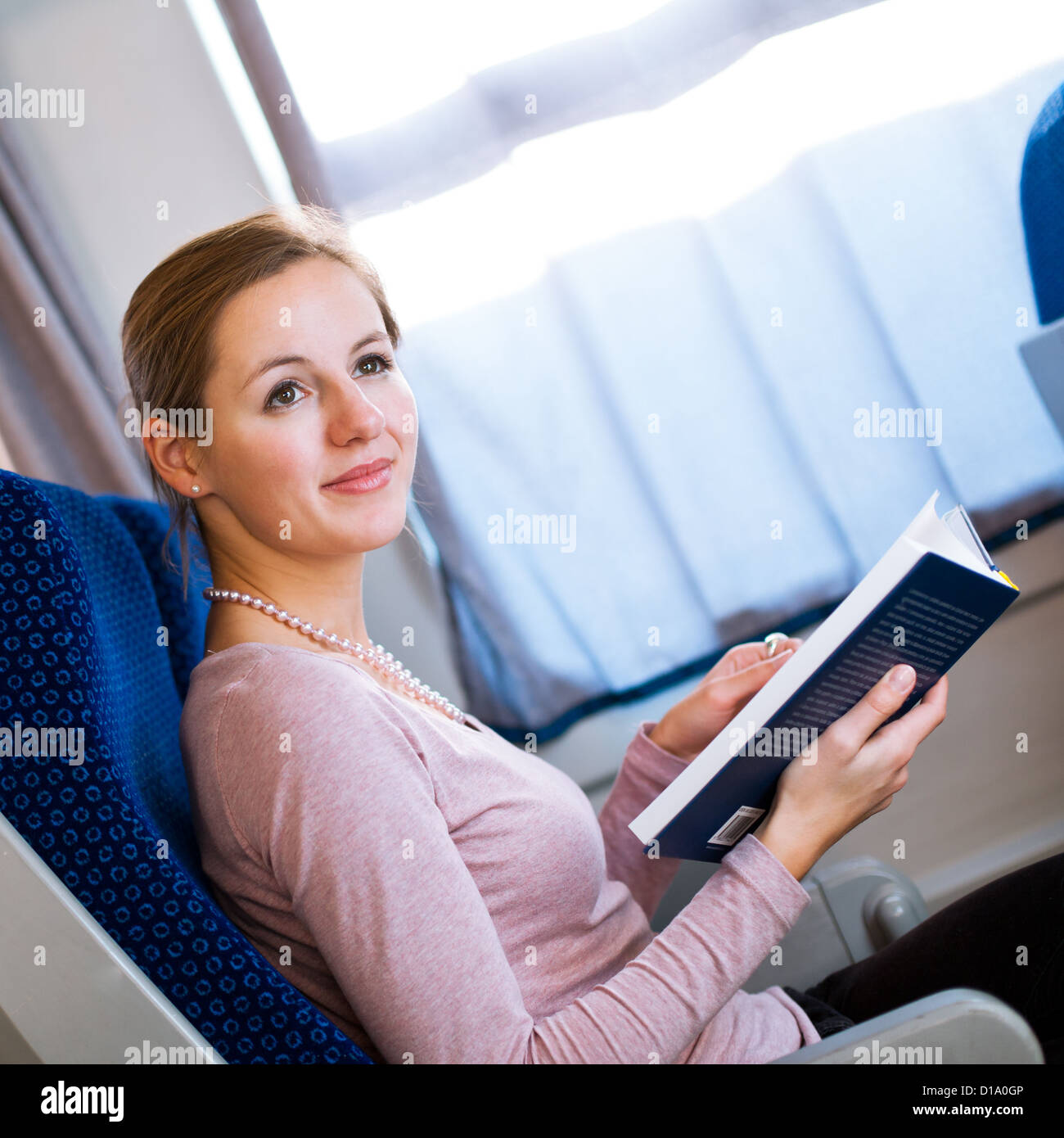 Young woman reading a book while on a train Stock Photo - Alamy