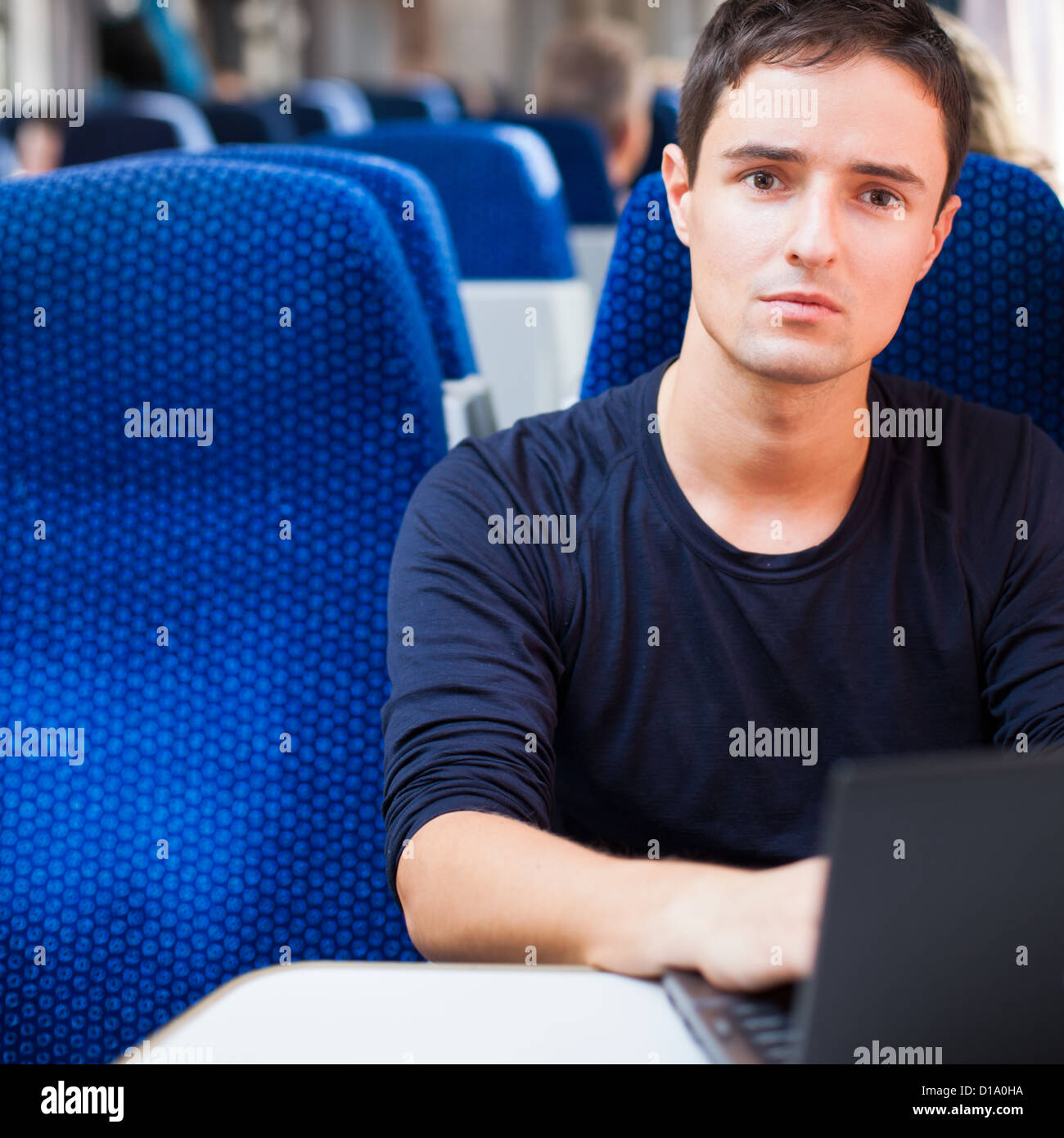 Handsome young man using his laptop computer while on the train ...