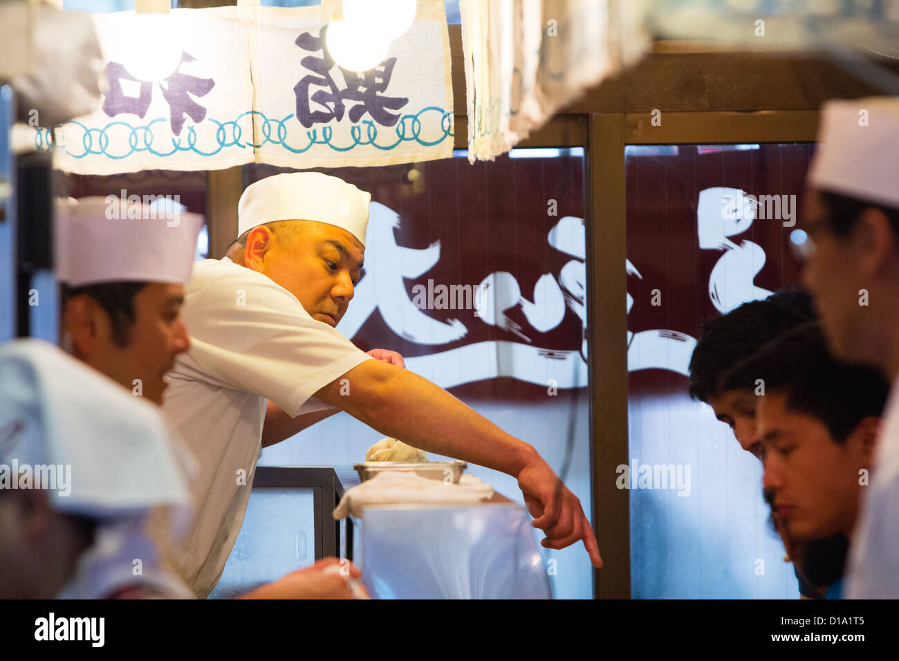 TOKYO, JAPAN Chefs and customers at a sushi restuarant at the Tsukiji ...