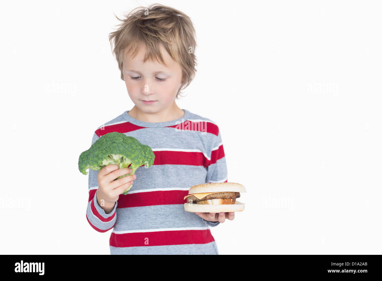Young boy holding broccoli and burger Stock Photo - Alamy