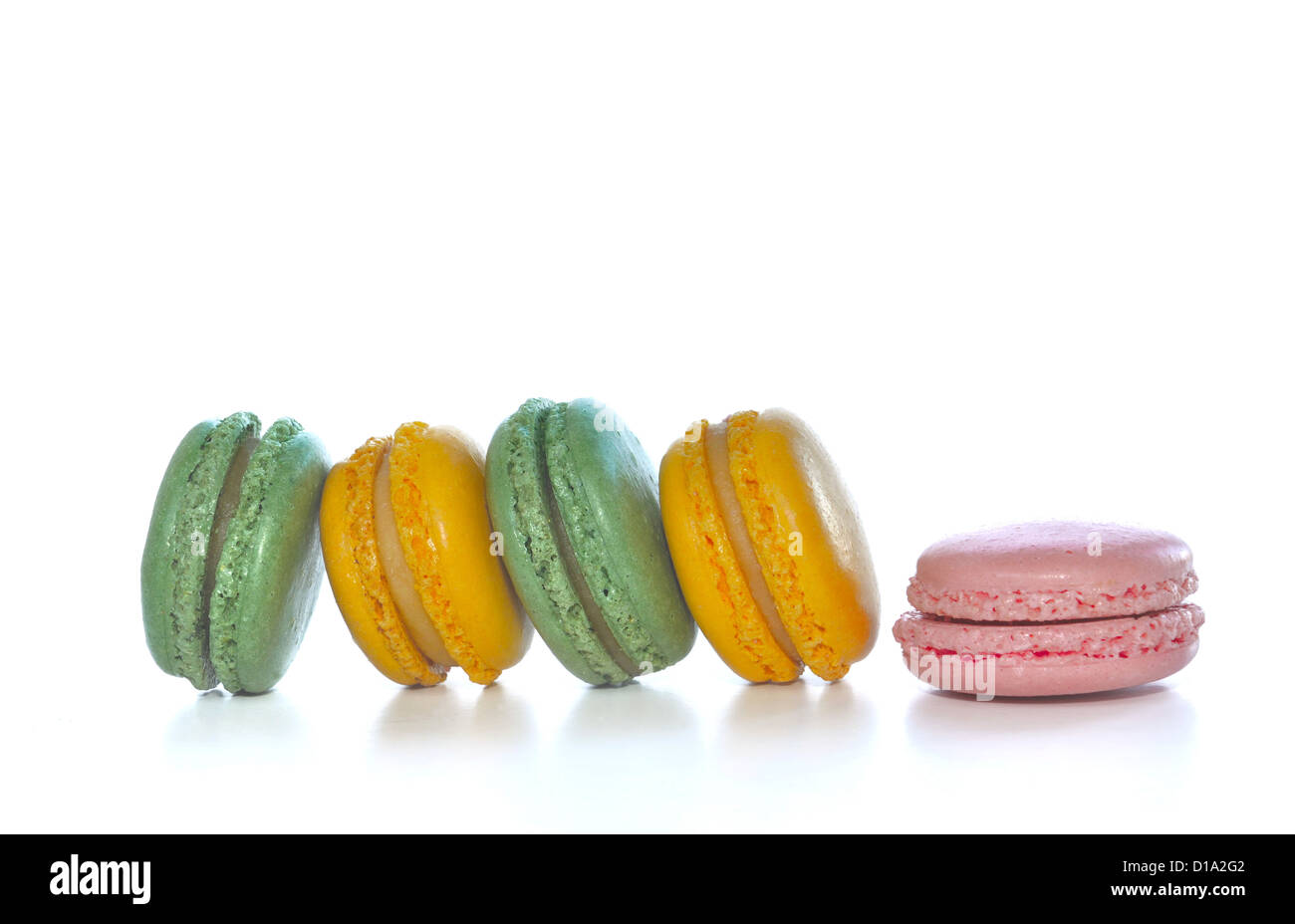 yellow and green macaroons standing and one pink on white background ...