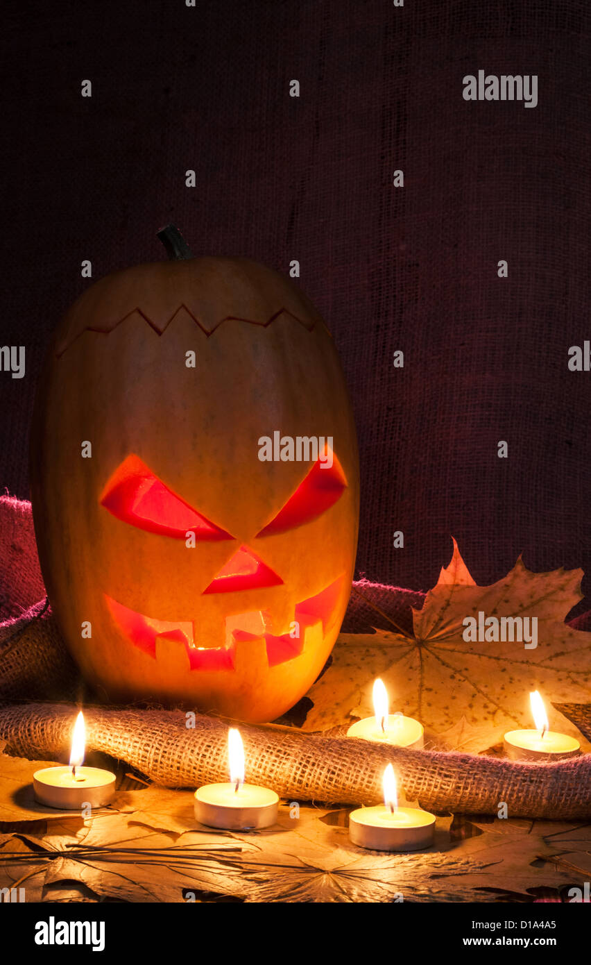 Halloween pumpkin on burlap background with candles and leaves lying on ...