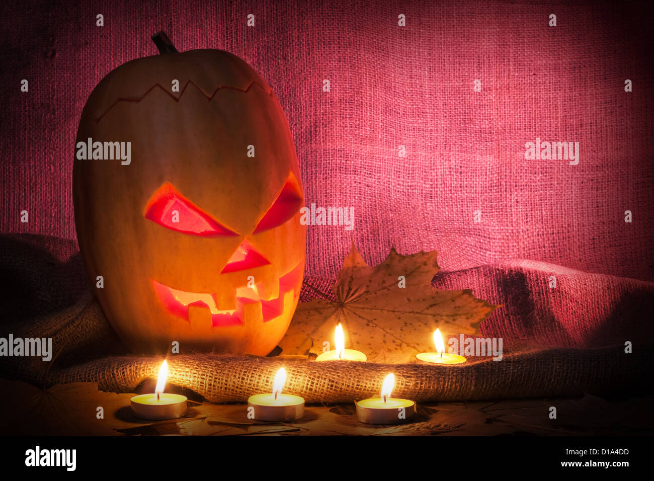 Halloween pumpkin on burlap background with candles and leaves lying on ...