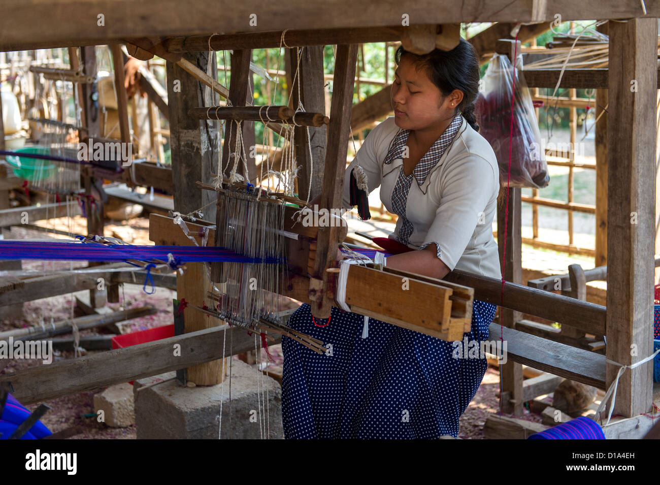 Young girl on the hand loom is weaving fabrics, on Inle Lake in Myanmar ...