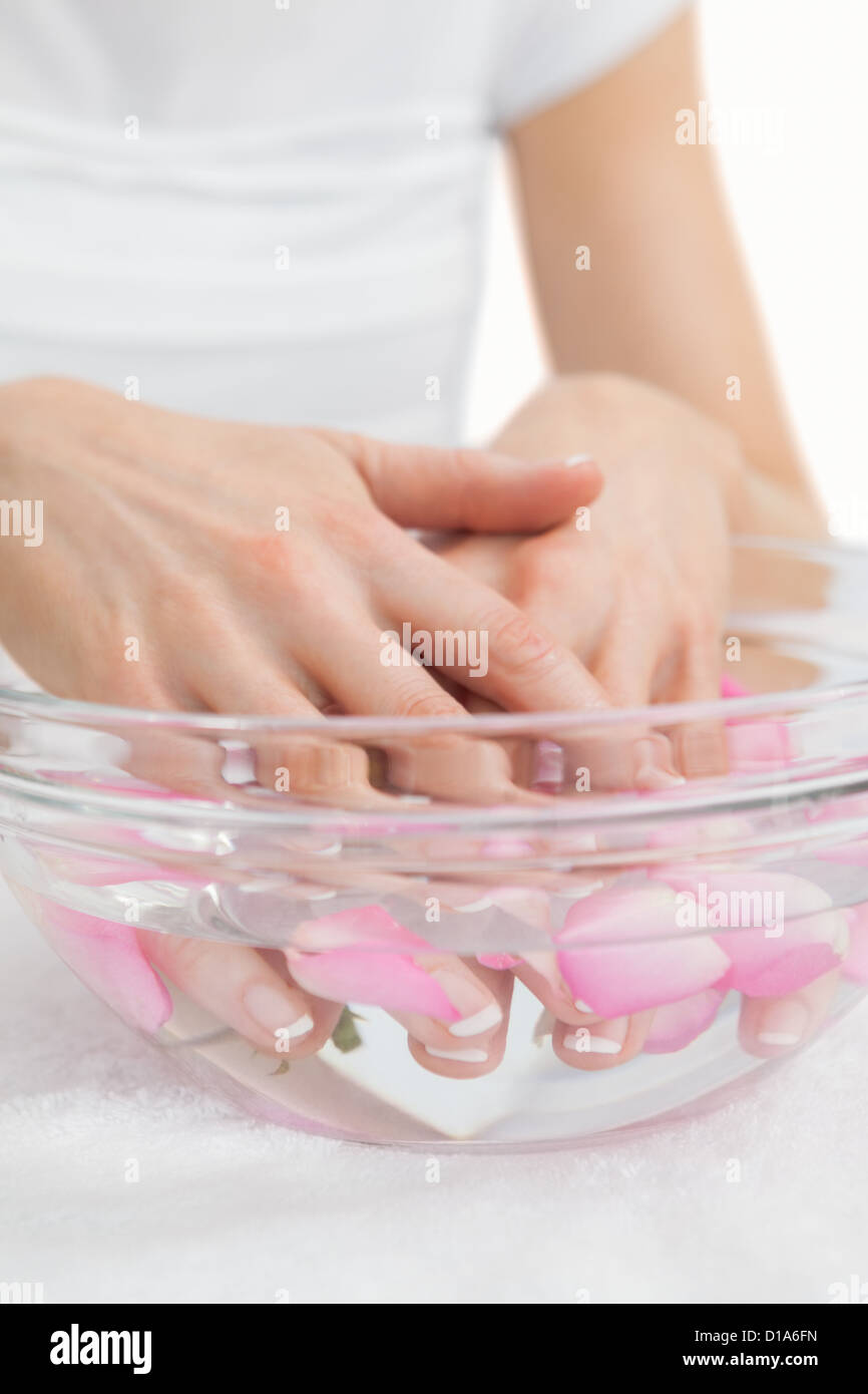 Womans hands in bowl with petals at hands spa Stock Photo - Alamy