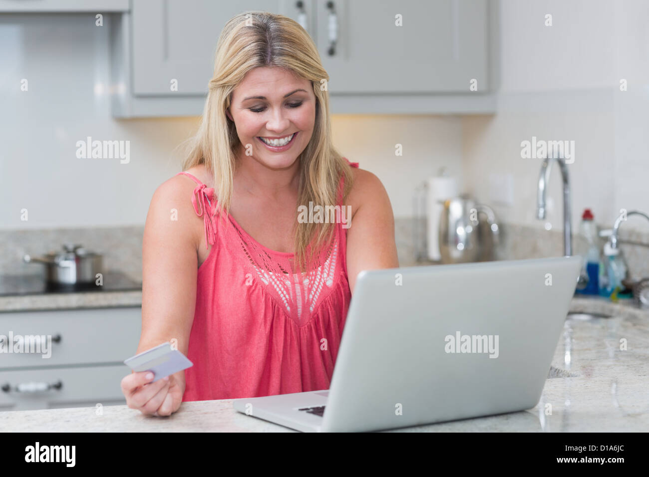 Woman doing online shopping in the kitchen Stock Photo - Alamy