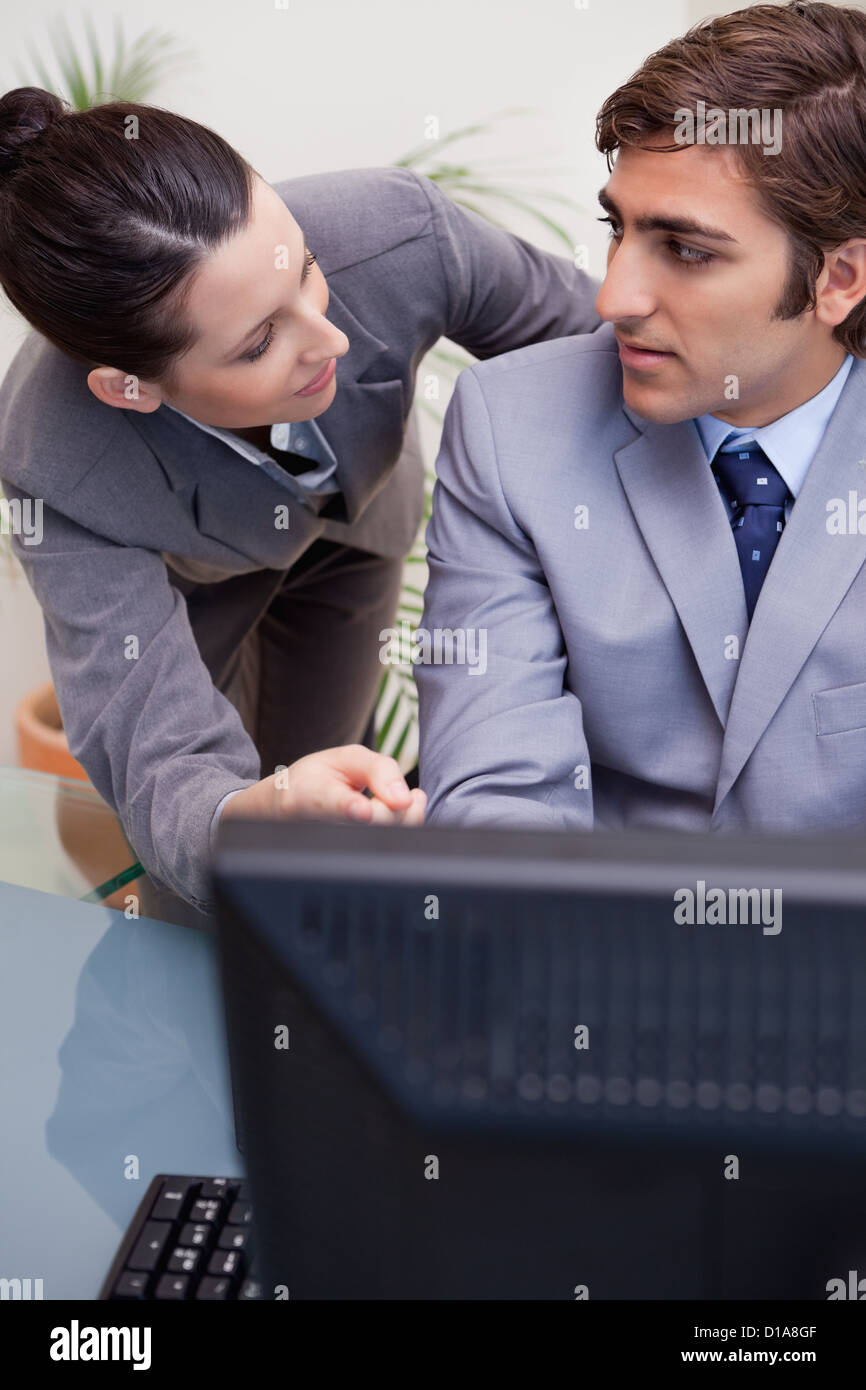 Colleagues in discussion while using computer at office Stock Photo - Alamy