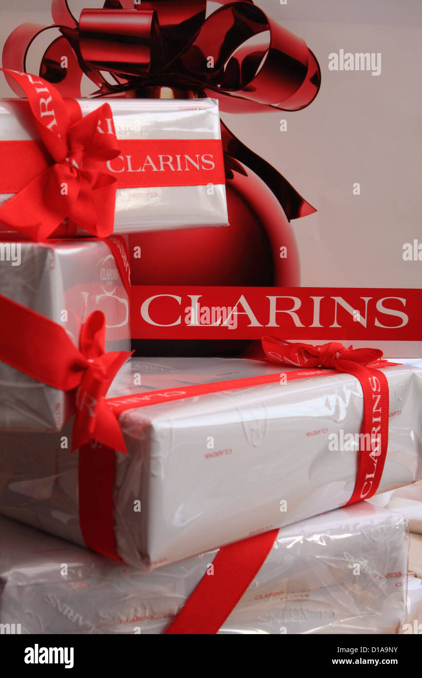 A pile of wrapped Clarins gifts in front of a Clarins shopping bag ...
