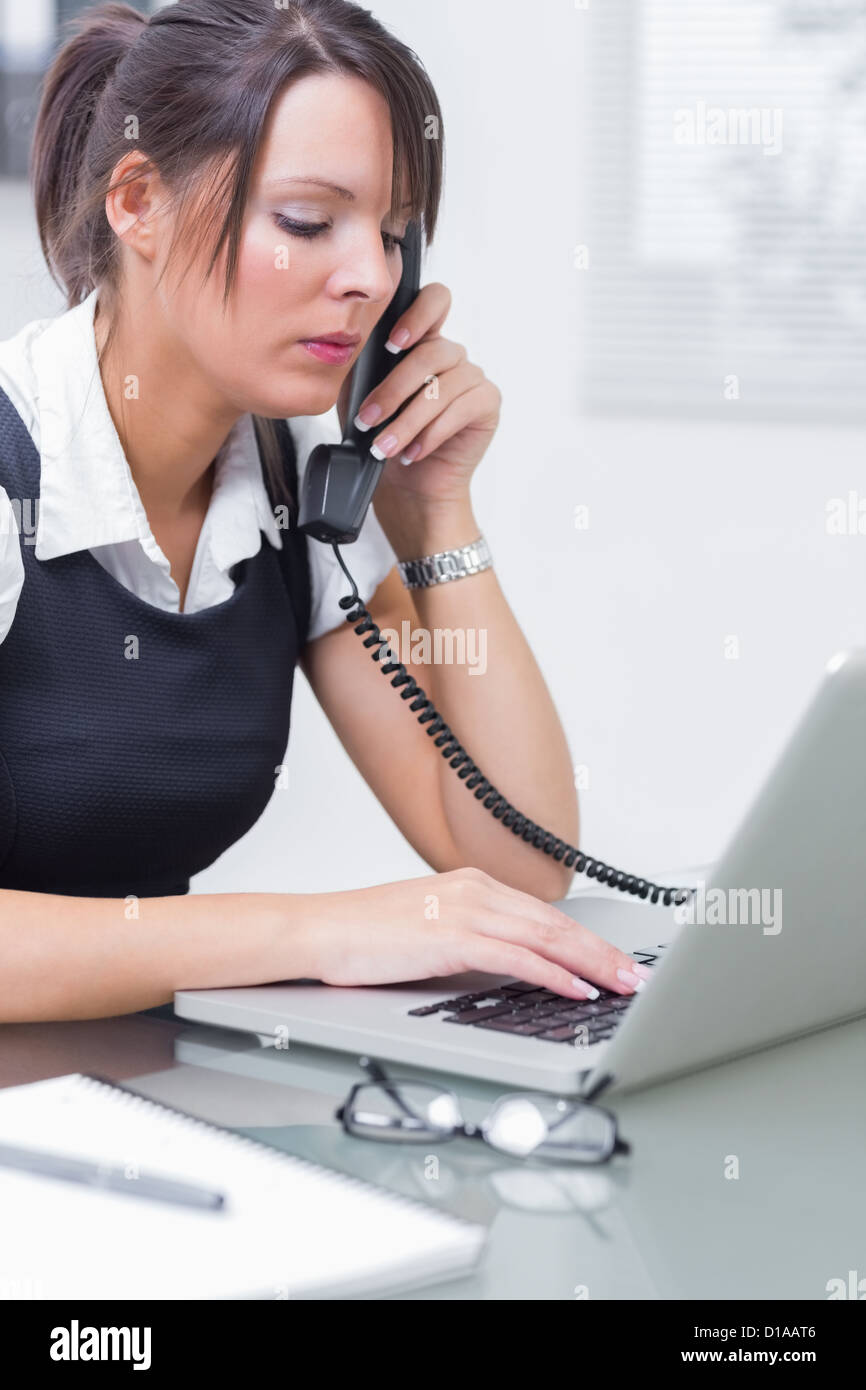 Business worker using landline and laptop Stock Photo - Alamy