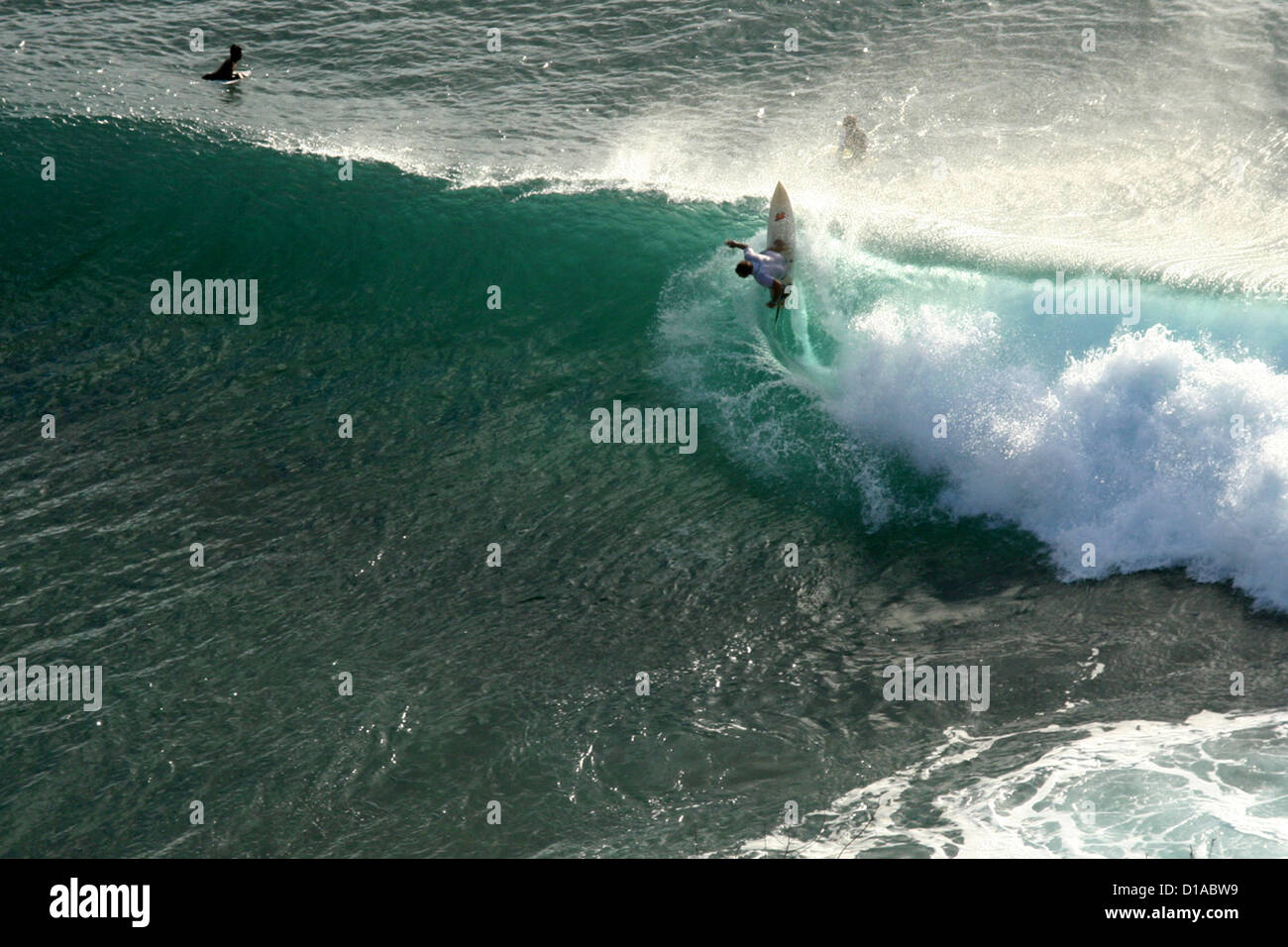 Surfers watching another surfer ride a radical wave, Maui, Hawaii Stock ...