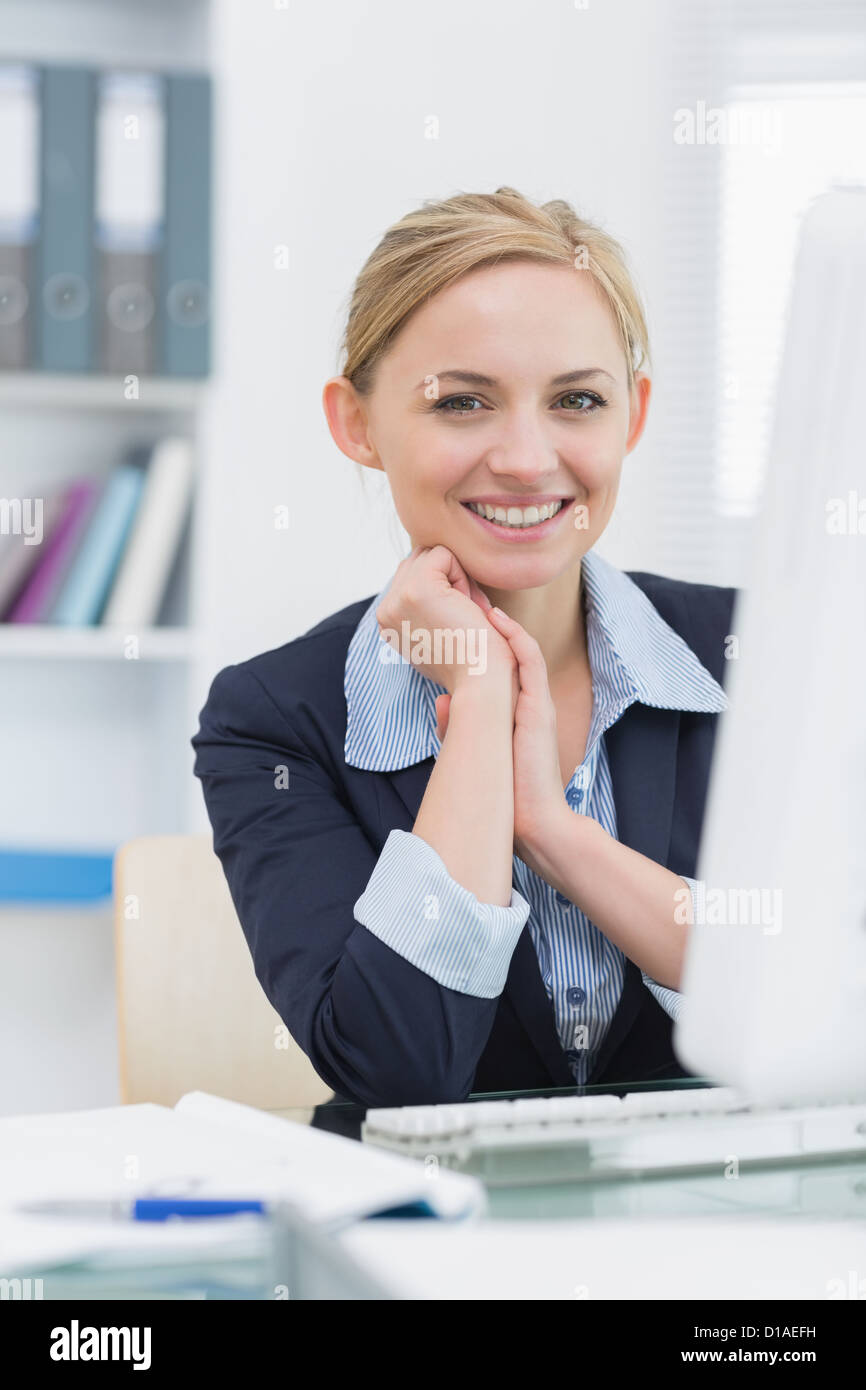 Smiling confident business woman with computer at office desk Stock ...
