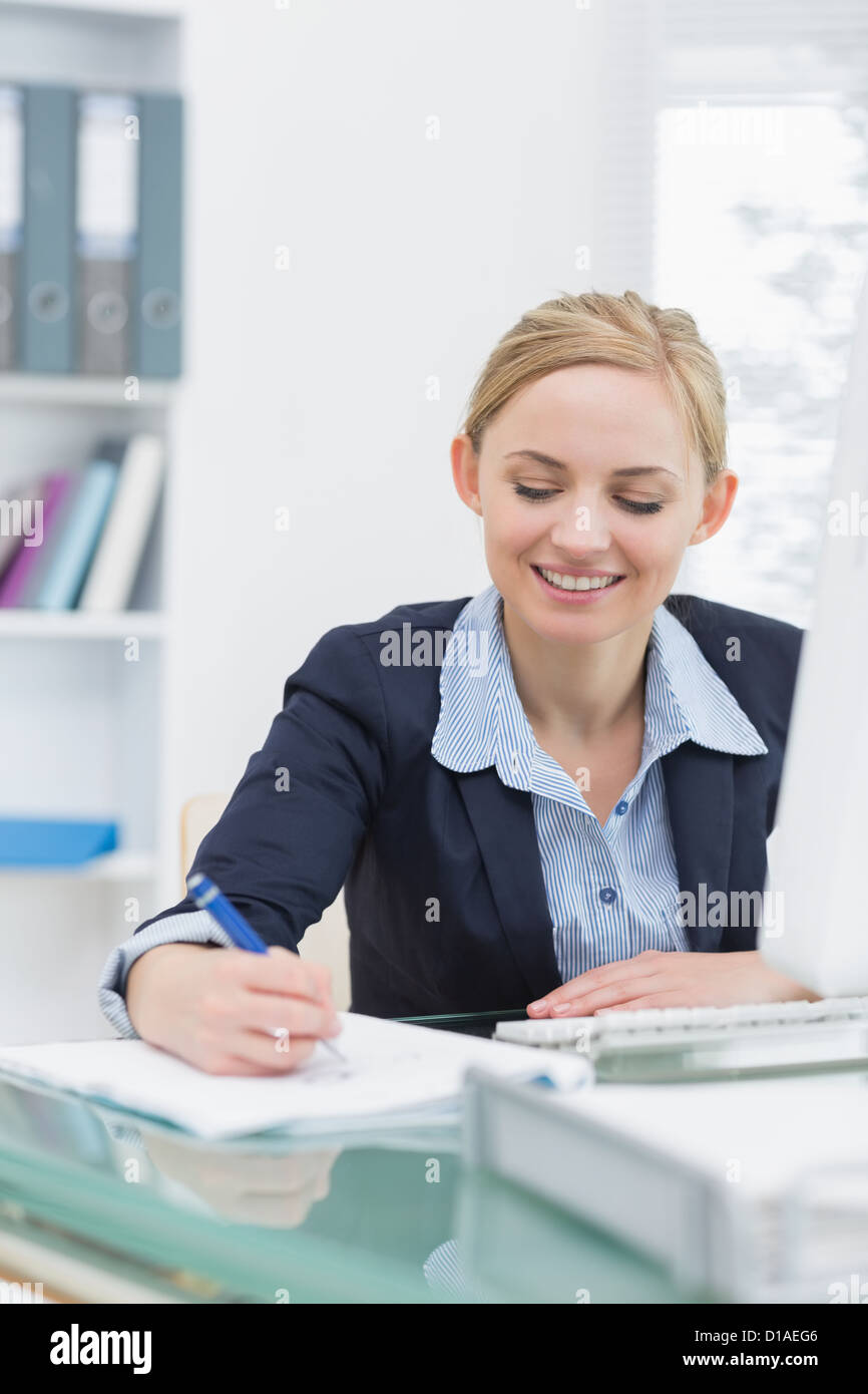 Business woman writing notes at office desk Stock Photo - Alamy