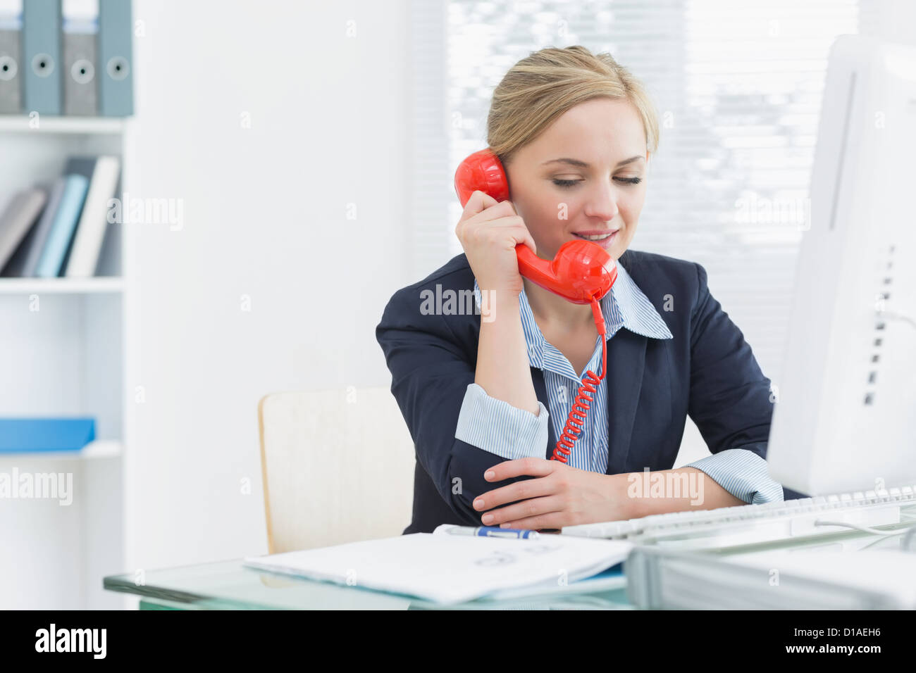 Female executive using red land line phone at desk Stock Photo - Alamy