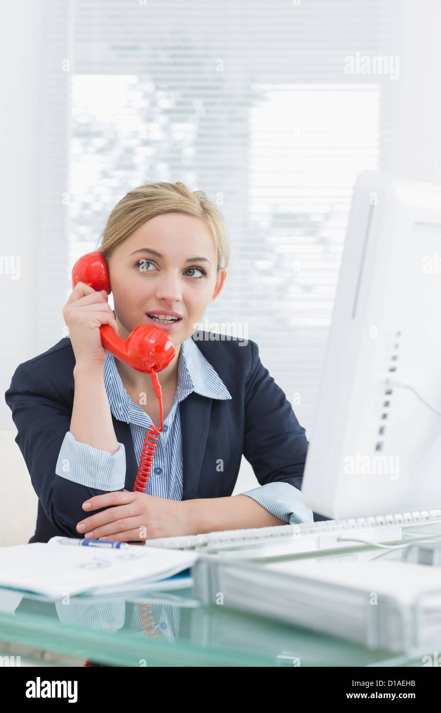 Female executive using red land line phone at desk Stock Photo - Alamy