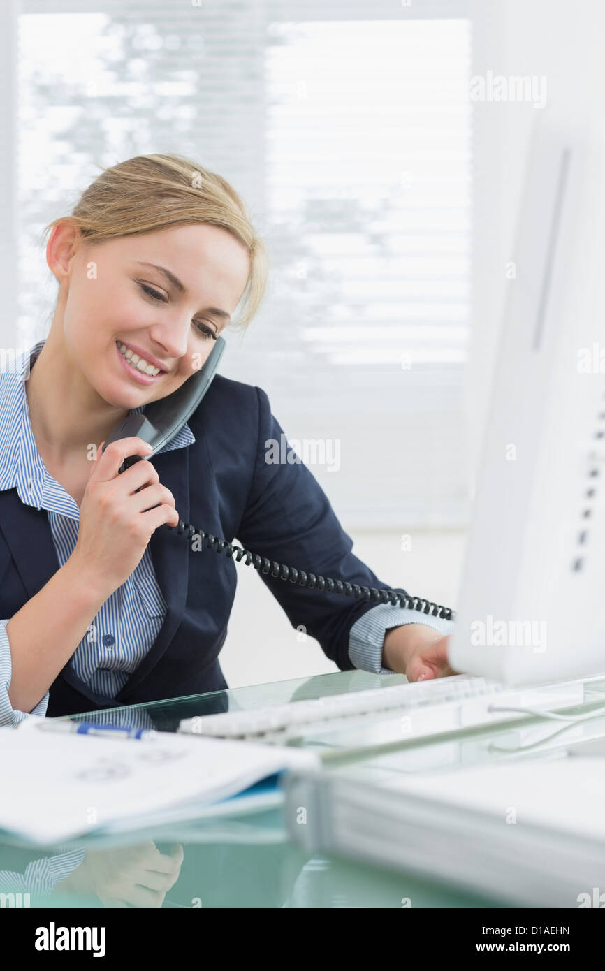 Female executive using landline phone and computer at desk Stock Photo ...