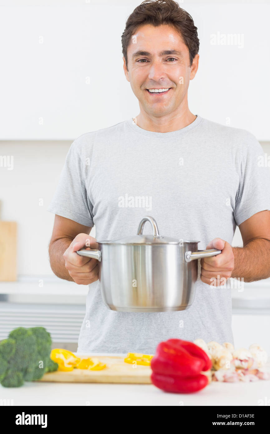 Man holding large pot in front of chopping board with vegetables Stock ...