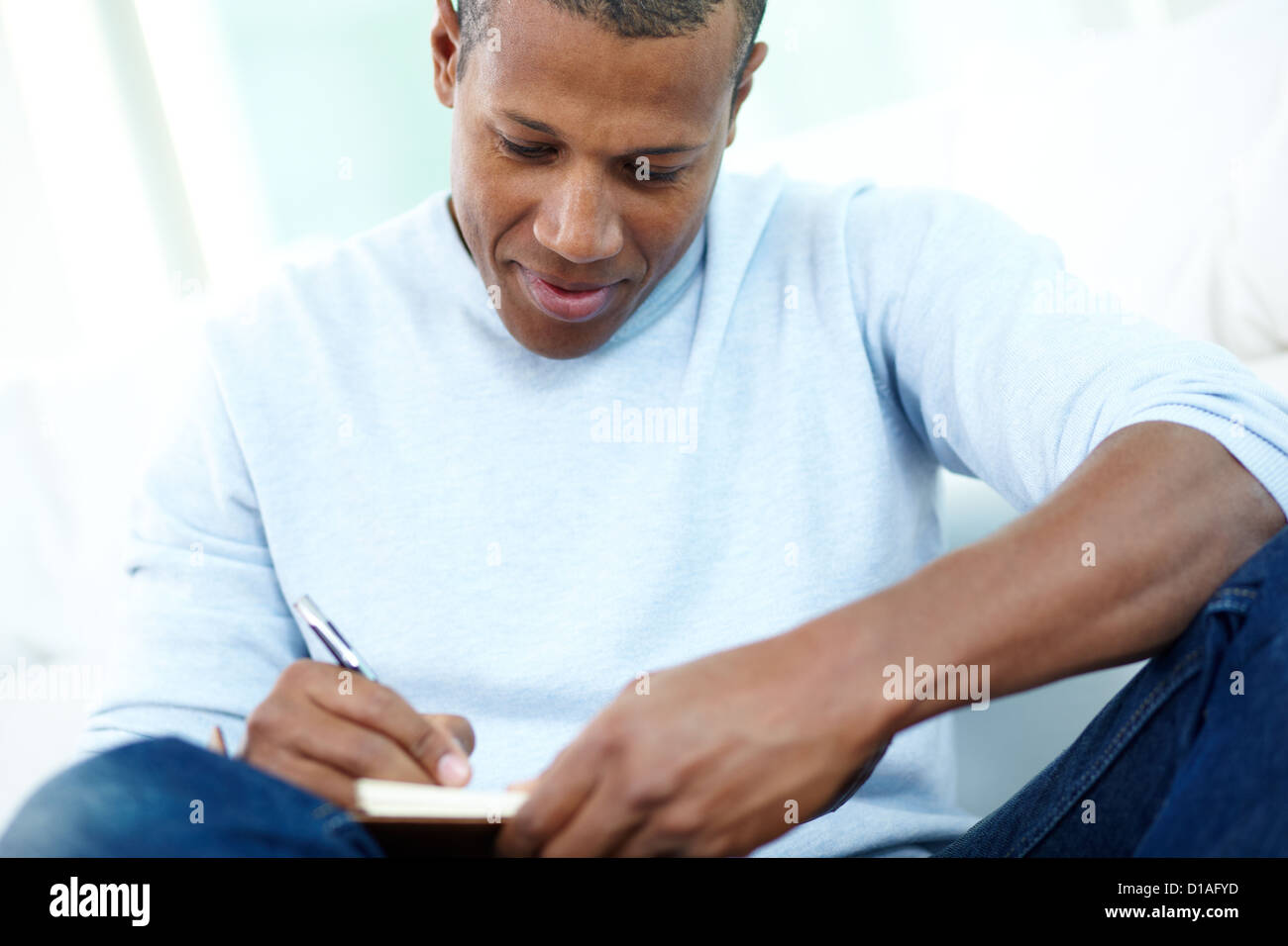 Image of young African man writing something in notepad Stock Photo - Alamy