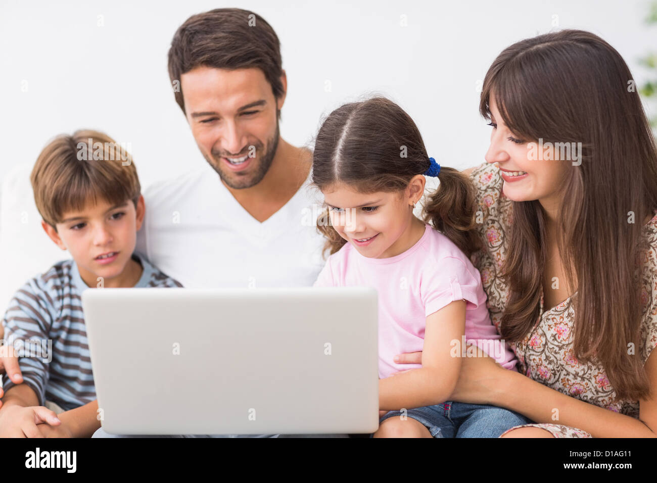 Smiling family using laptop on couch Stock Photo - Alamy