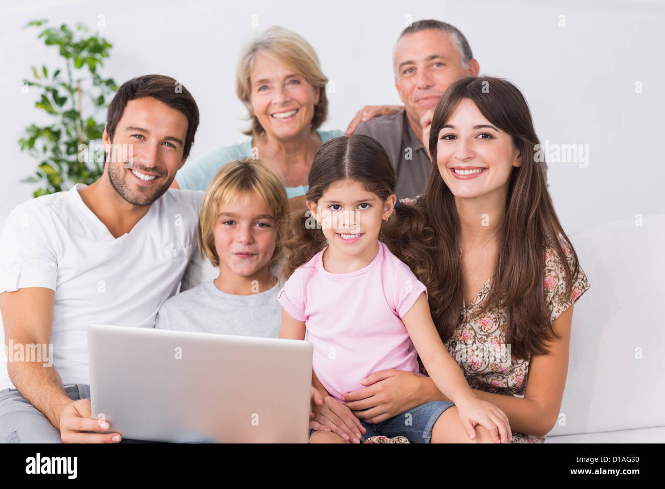 Happy family on couch using laptop Stock Photo - Alamy
