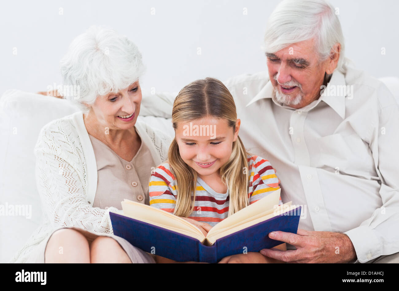 Granddaughter reading book with grandparents Stock Photo - Alamy