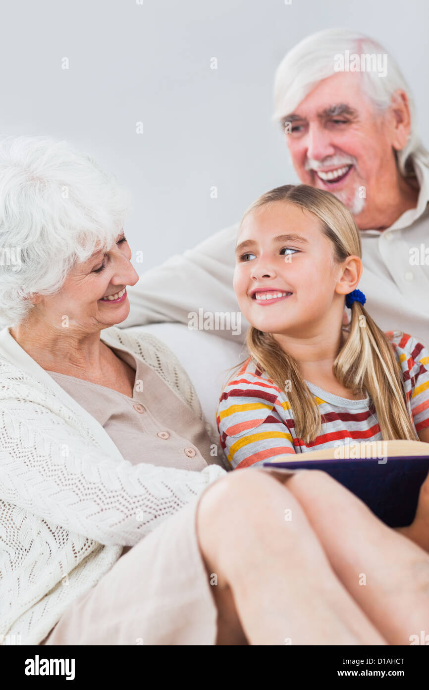 Happy grandparents reading with granddaughter Stock Photo - Alamy